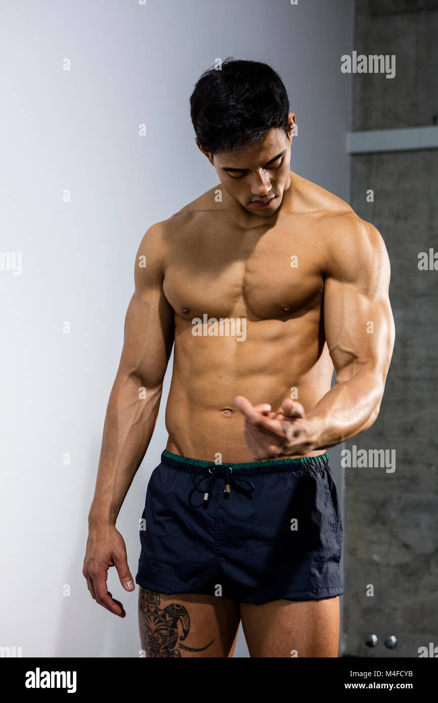 An Asian Fitness Model Flexing His Bicep Muscle And Looking At It Stock