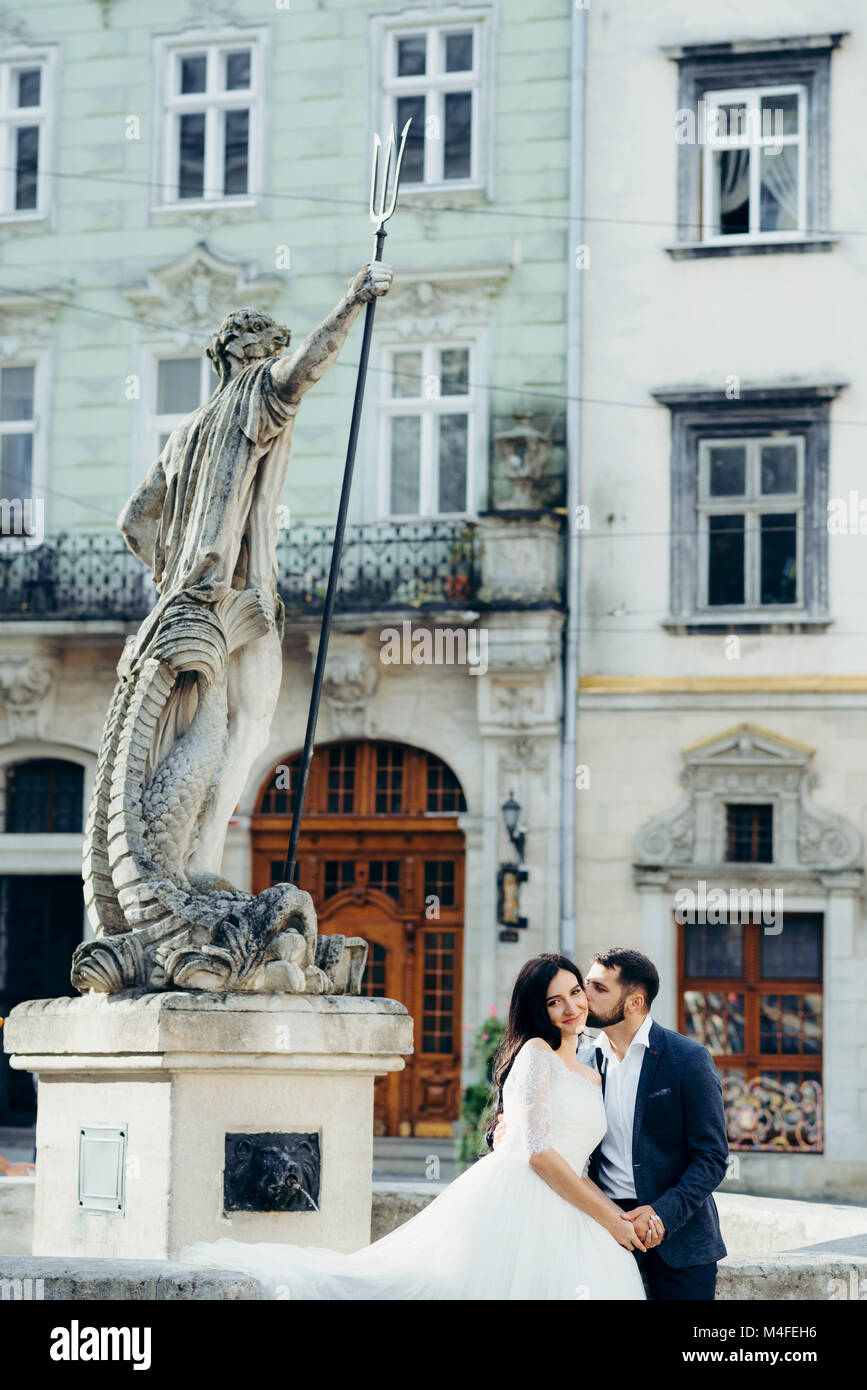 Vertical wedding portrait of the handsome groom softly kissing the ...