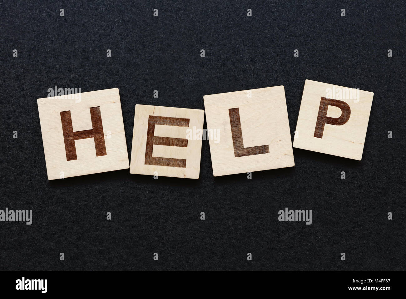 Close up word HELP on wooden letter signs over black board background ...