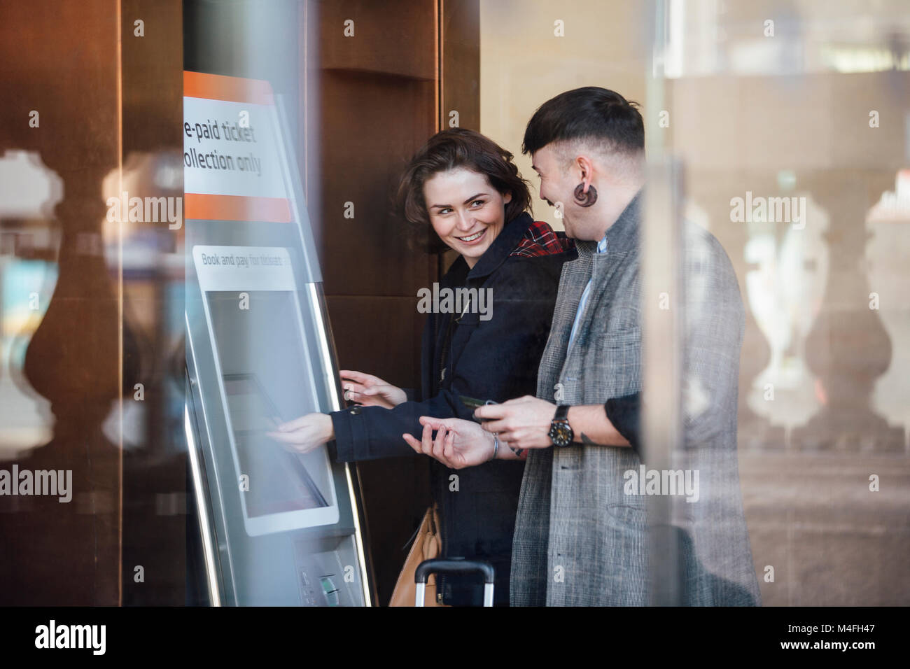 Couple are buying tickets for their train using an electronic ticket ...