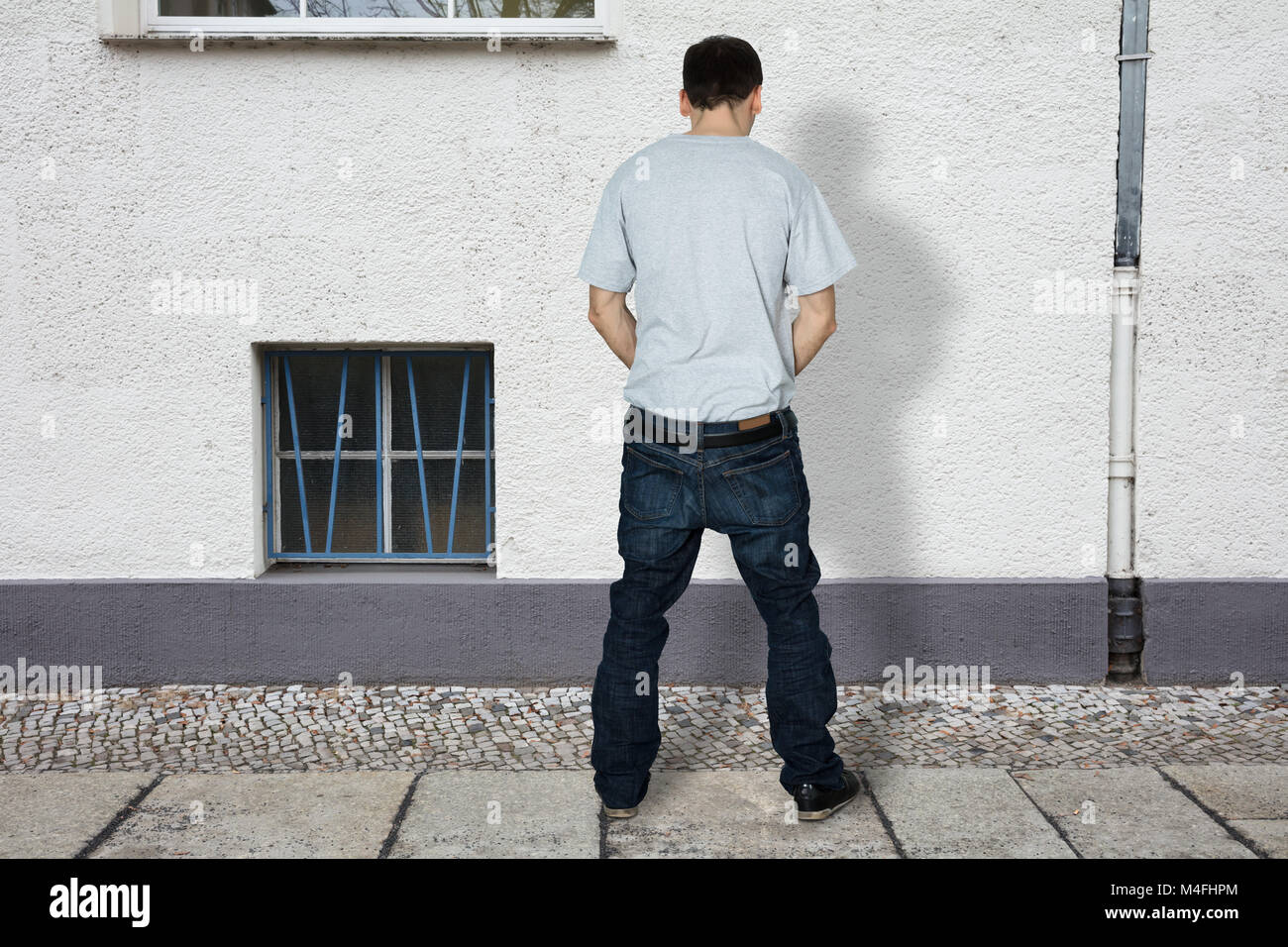 Rear View Of A Man Peeing On The Wall Of A Building Stock Photo - Alamy