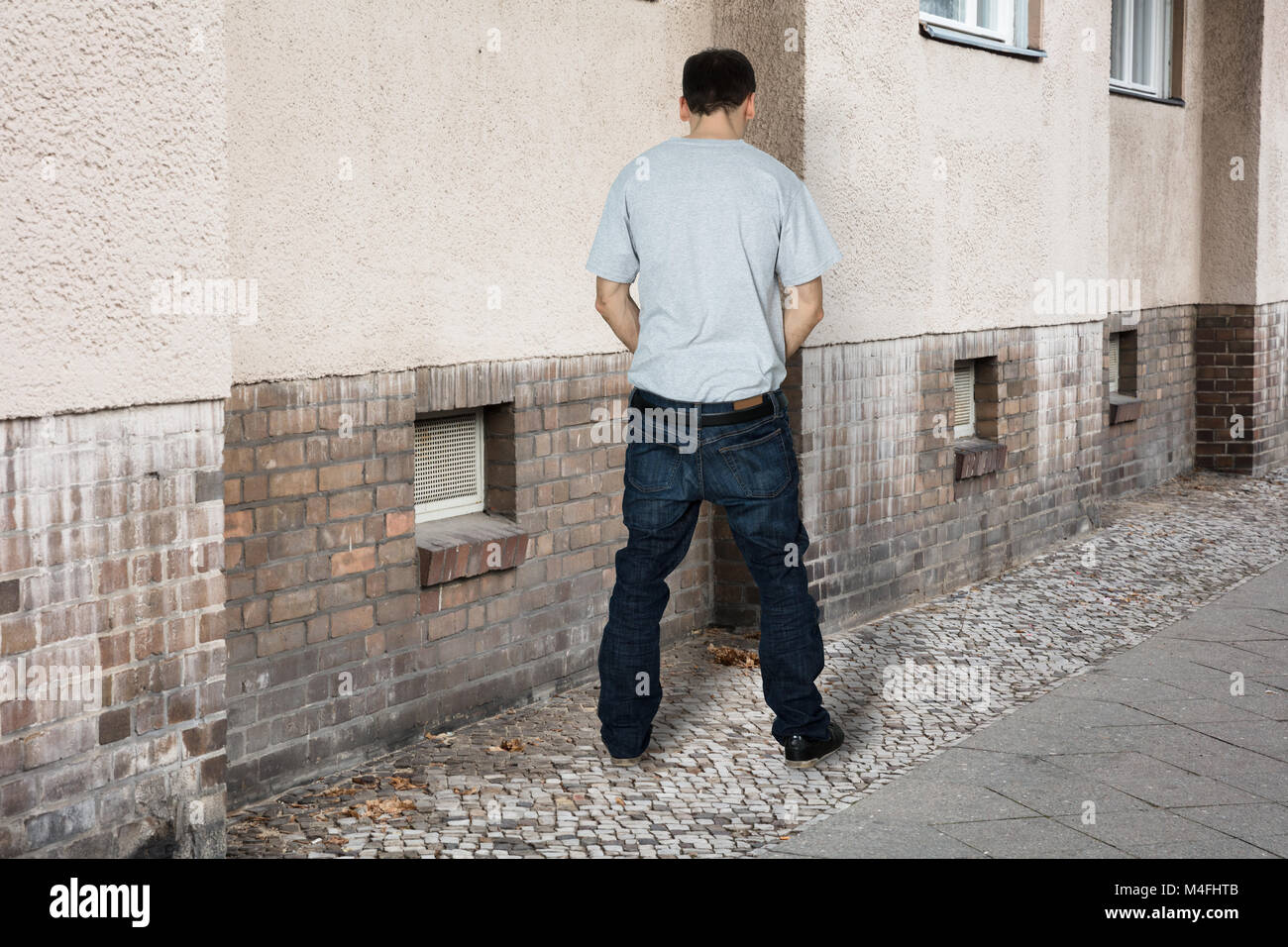 Rear View Of A Man Peeing On The Wall Of A Building Stock Photo - Alamy