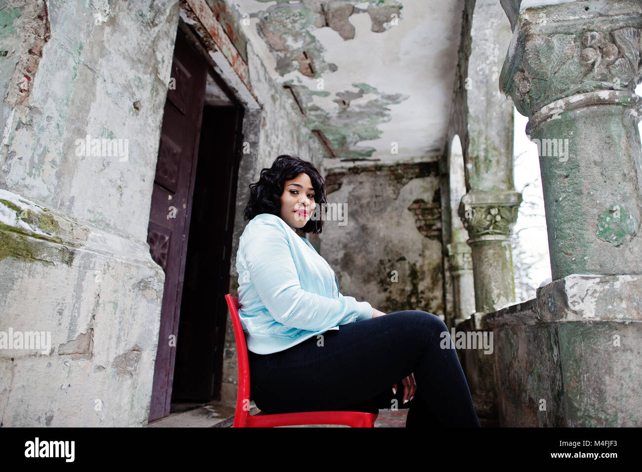 Stylish african american plus size model sitting on red chair outdoor ...