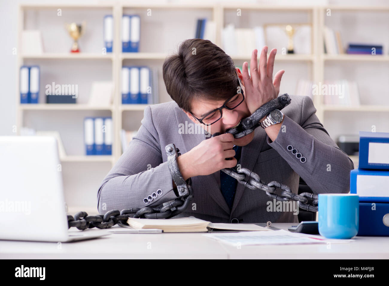Businessman tied with chains to his work Stock Photo - Alamy