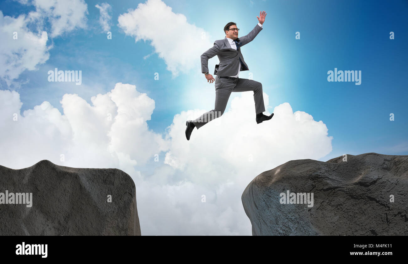 Ambitious businessman jumping over the cliff Stock Photo - Alamy