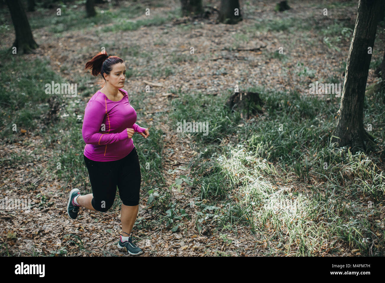 Front view of a focused female runner trying to stay fit and jogging in ...