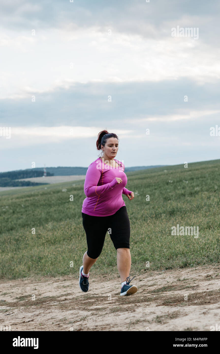 A full length portrait of a determined female runner running up a hill ...