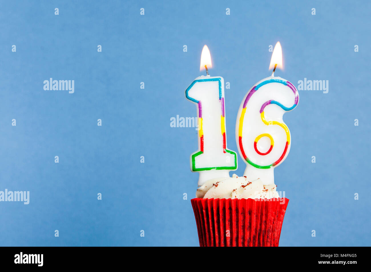 Number 16 birthday candle in a cupcake against a blue background Stock ...