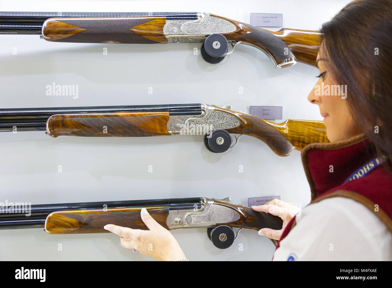 womman standing in front of a display of shotguns Stock Photo - Alamy