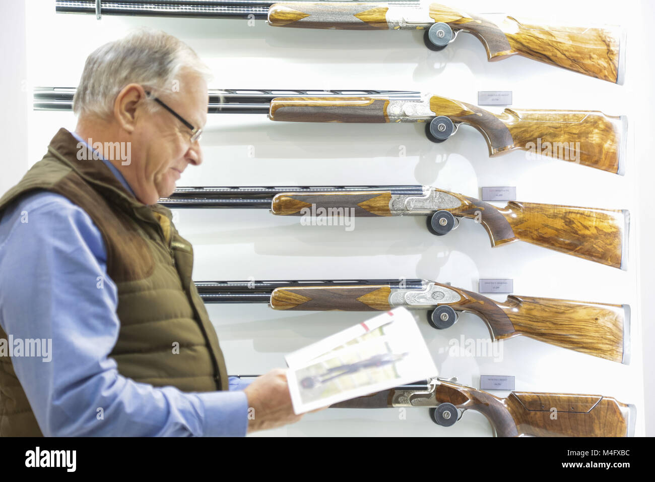 man standing in front of a display of shotguns Stock Photo - Alamy
