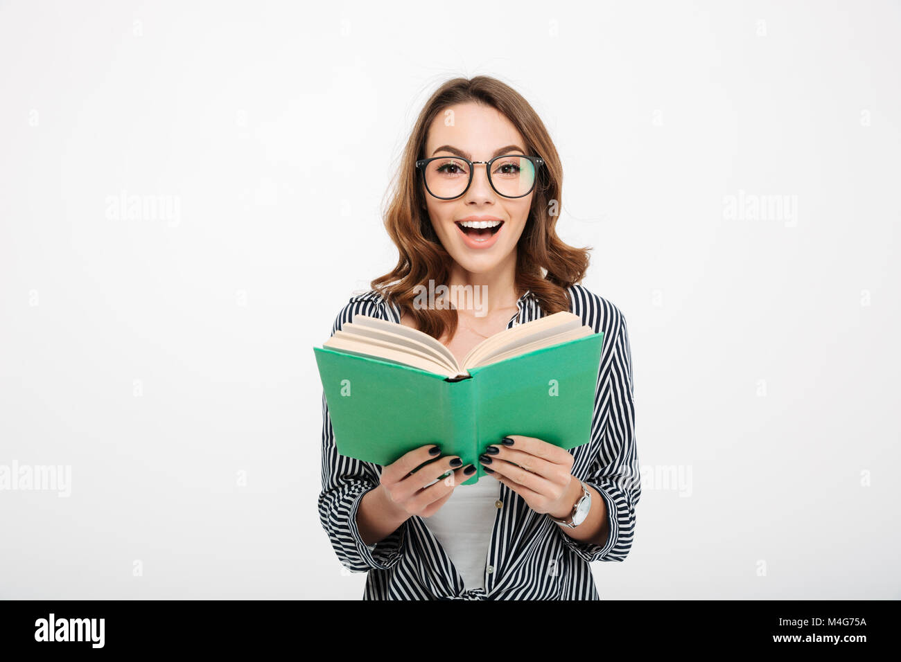Portrait of a cheerful casual girl holding book and laughing isolated ...