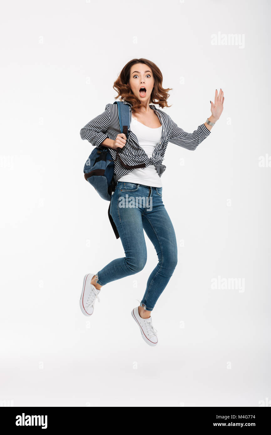 Photo of shocked young lady jumping isolated over white wall background ...
