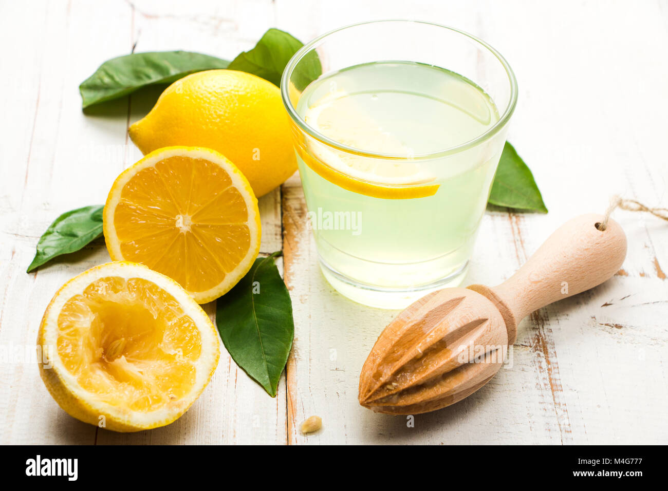 Natural lemonade with wooden reamer and lemon tree leaves on a white ...
