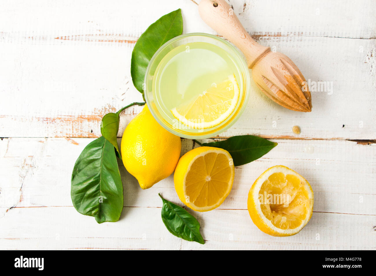 Natural lemonade with wooden reamer and lemon tree leaves on a white ...