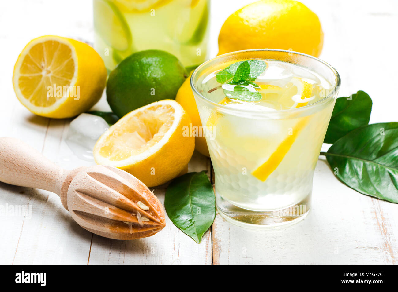 Natural lemonade with lemon, lime and mint with wooden reamer and lemon ...