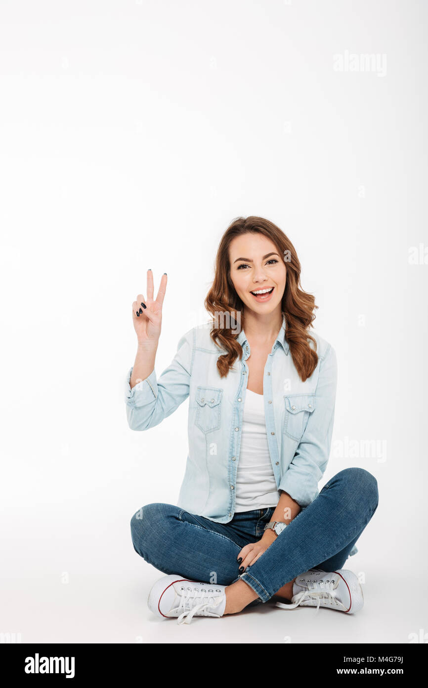 Photo of cheerful young woman sitting isolated over white wall ...