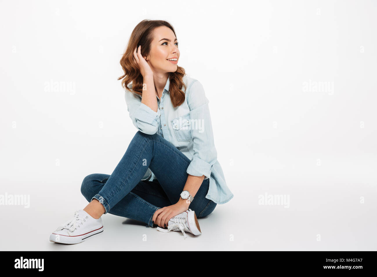 Photo of happy young woman sitting isolated over white wall background ...