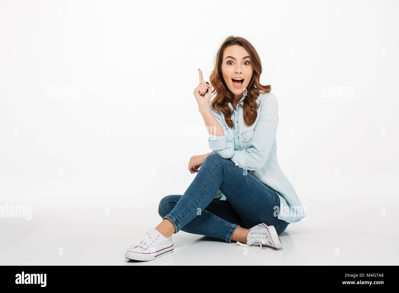 Photo of happy young woman sitting isolated over white wall background ...