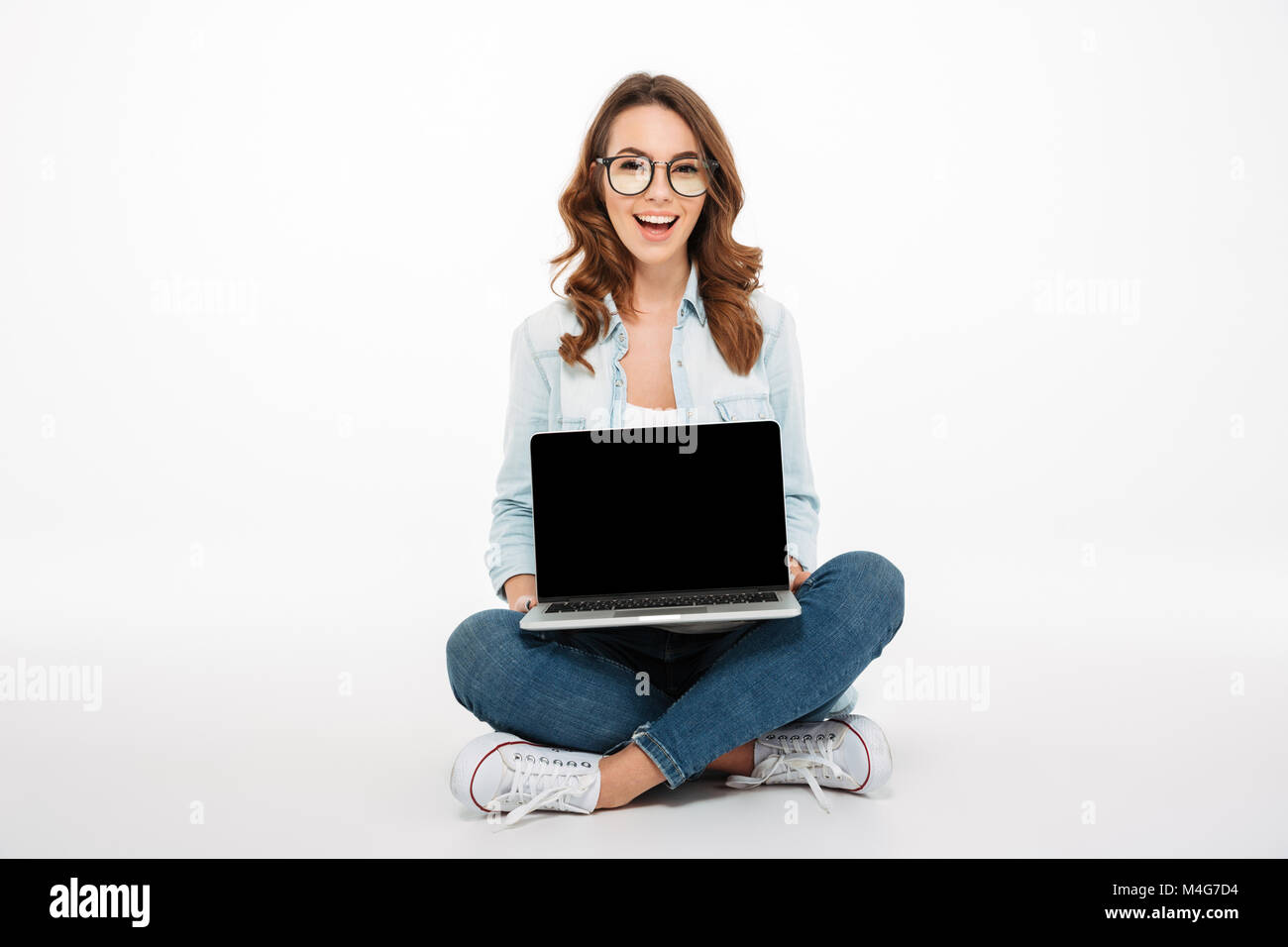 Portrait of a pretty casual girl showing blank screen laptop computer ...