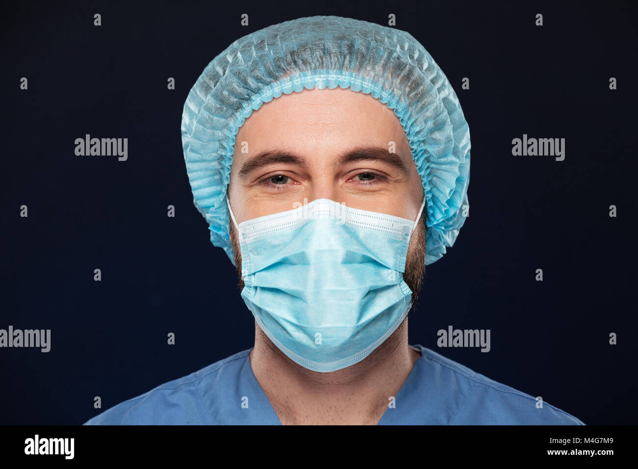 Close up portrait of a male surgeon wearing face mask and sterile hat ...