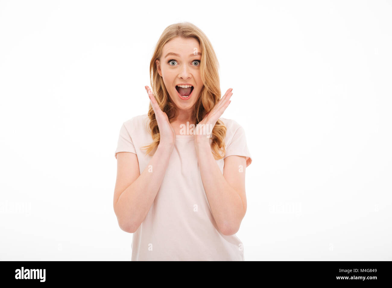 Photo of beautiful young surprised woman standing isolated over white ...