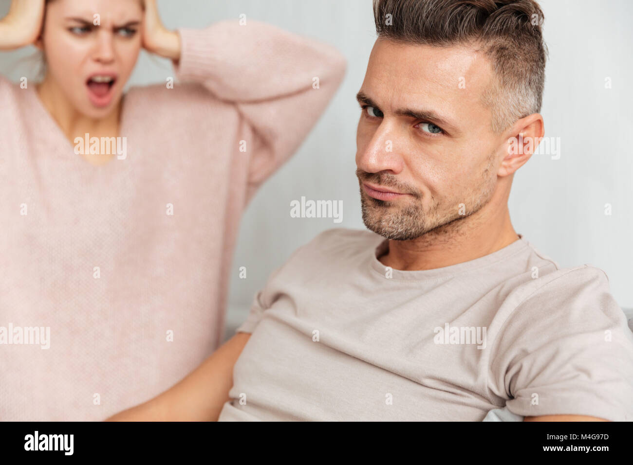 Close up image of Confused man sitting on couch with his girlfriend ...