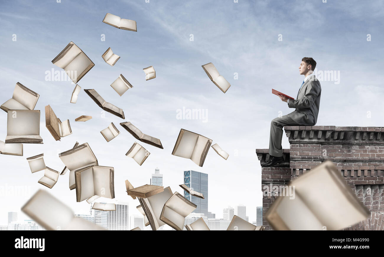 Man on roof reading book and many of them flying in air Stock Photo - Alamy