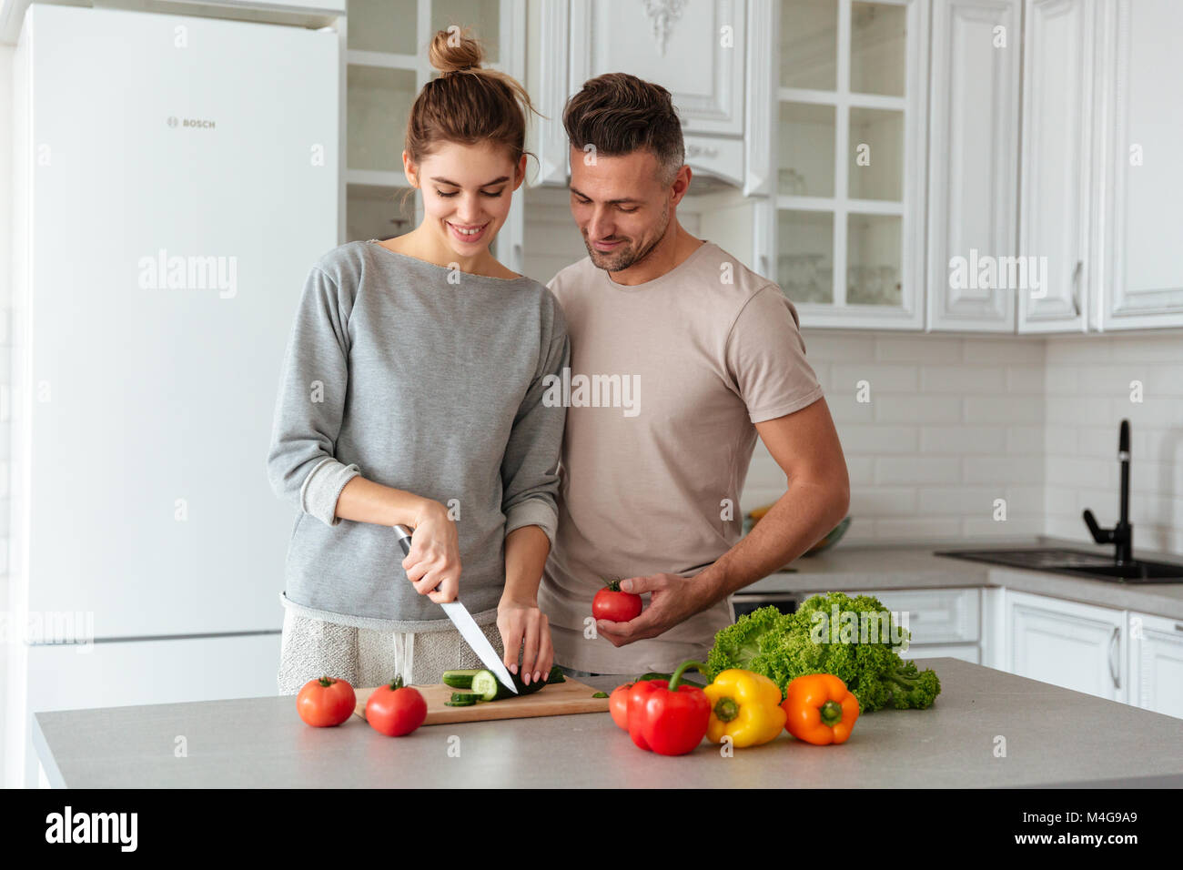 Portrait of a smiling loving couple cooking salad together while ...