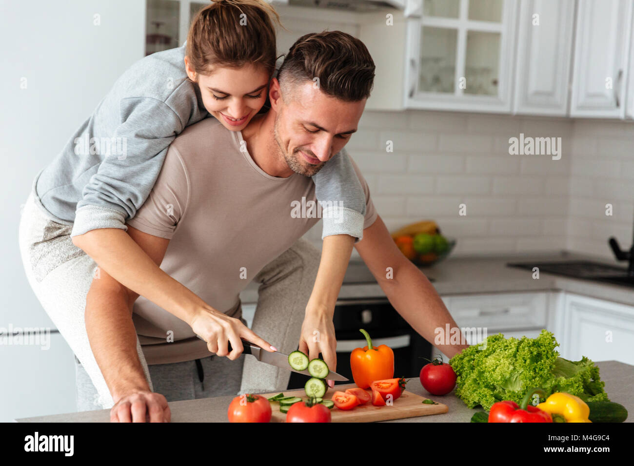 Portrait of a smiling loving couple cooking salad together while ...