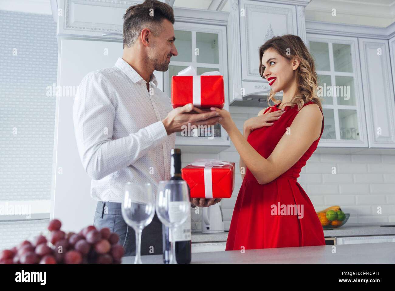 Portrait of a loving pretty smart dressed couple giving presents to ...