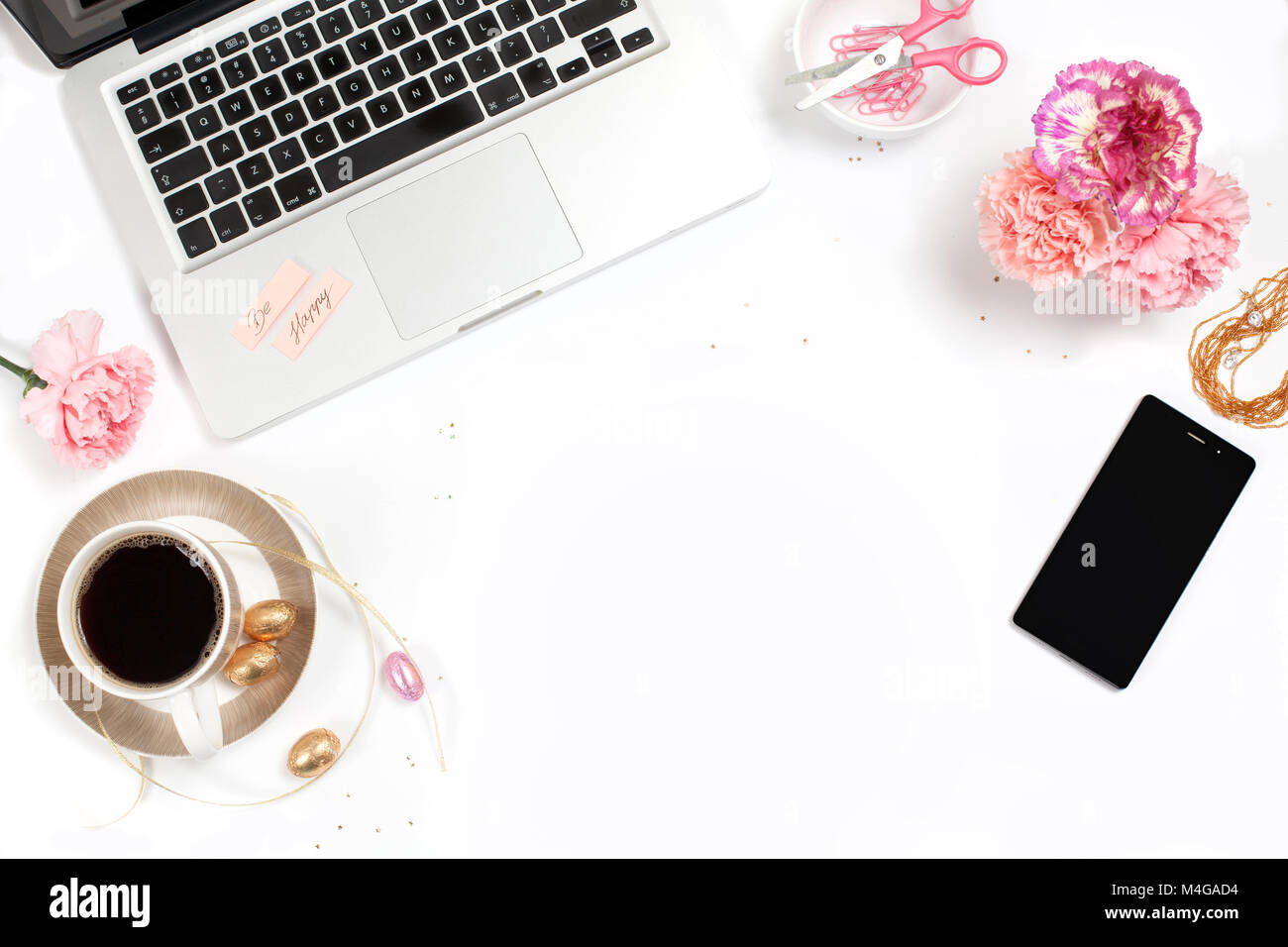 White, gold and pink womens office desk table with a lot of things on ...