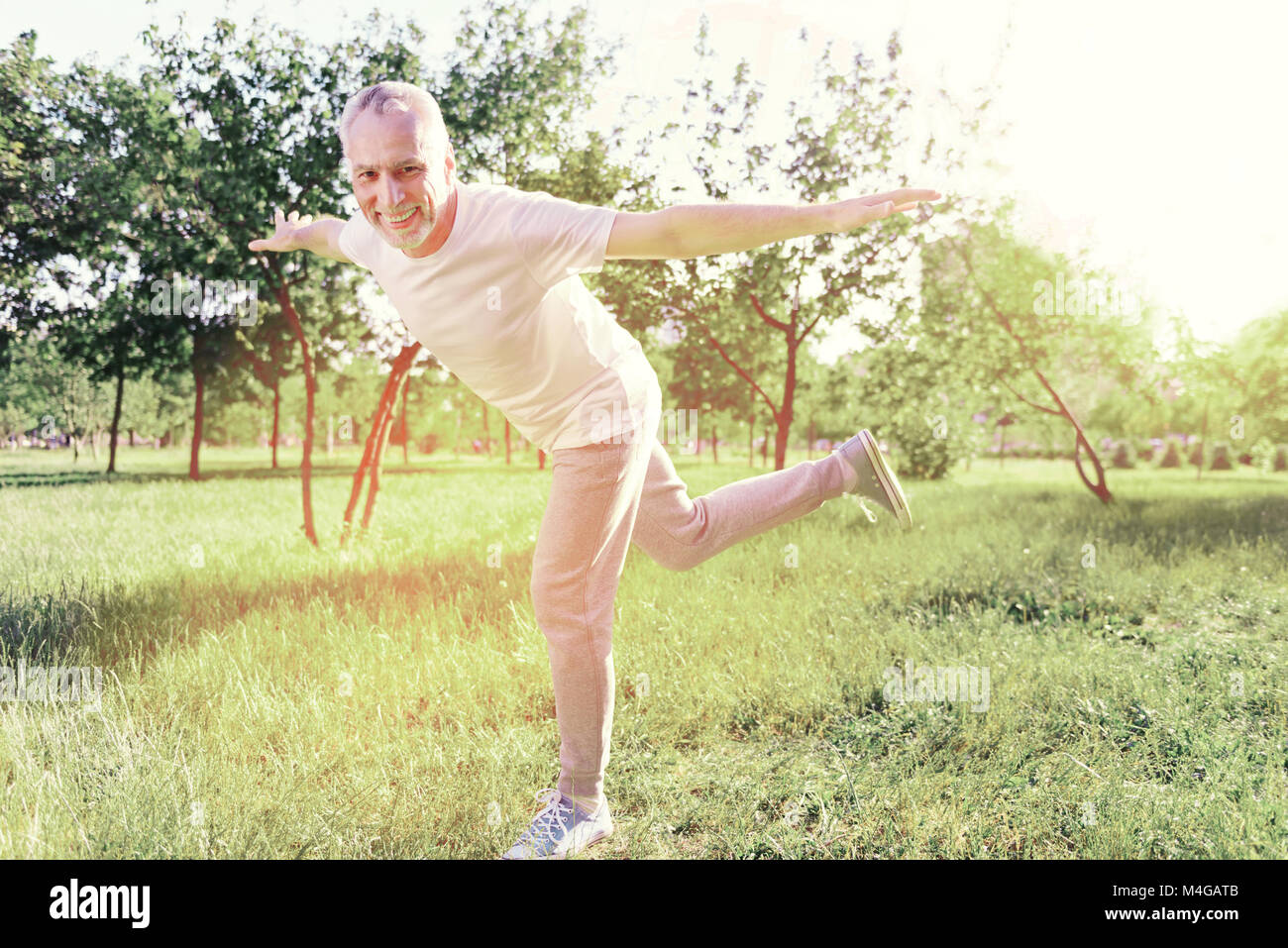 Positive man keeping his body in bird position Stock Photo - Alamy