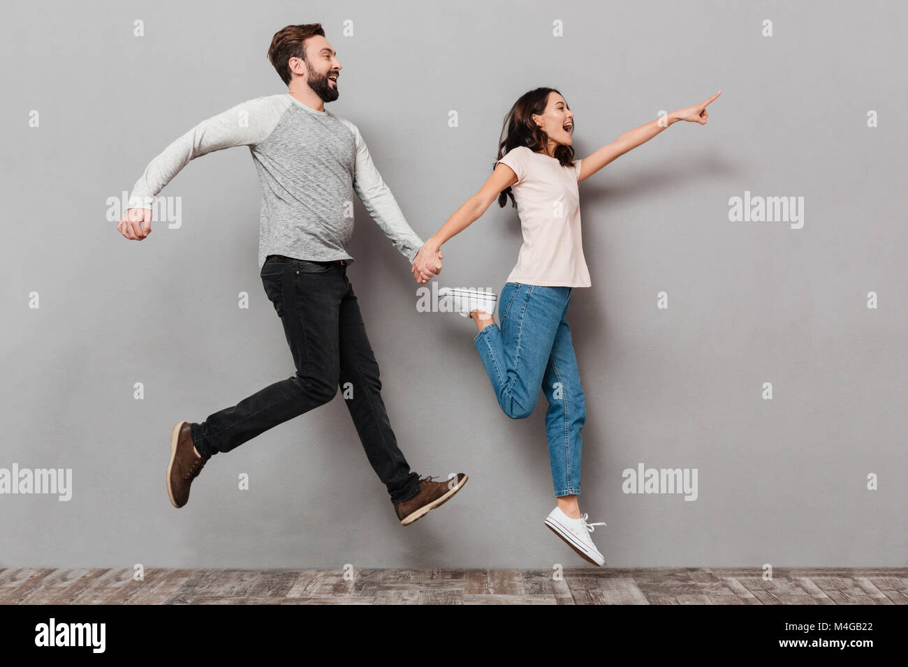 Full length portrait of a joyful young couple jumping together and ...