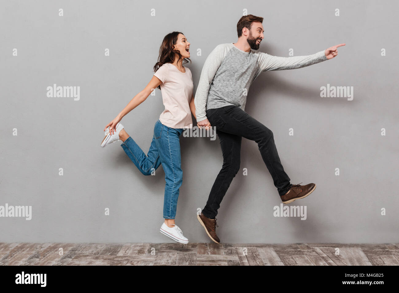 Full length portrait of an excited young couple jumping together and ...