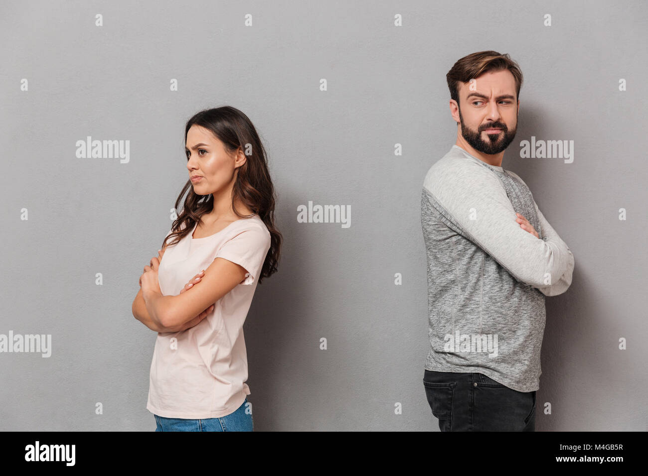 Portrait of a disappointed young couple having an argument over gray ...