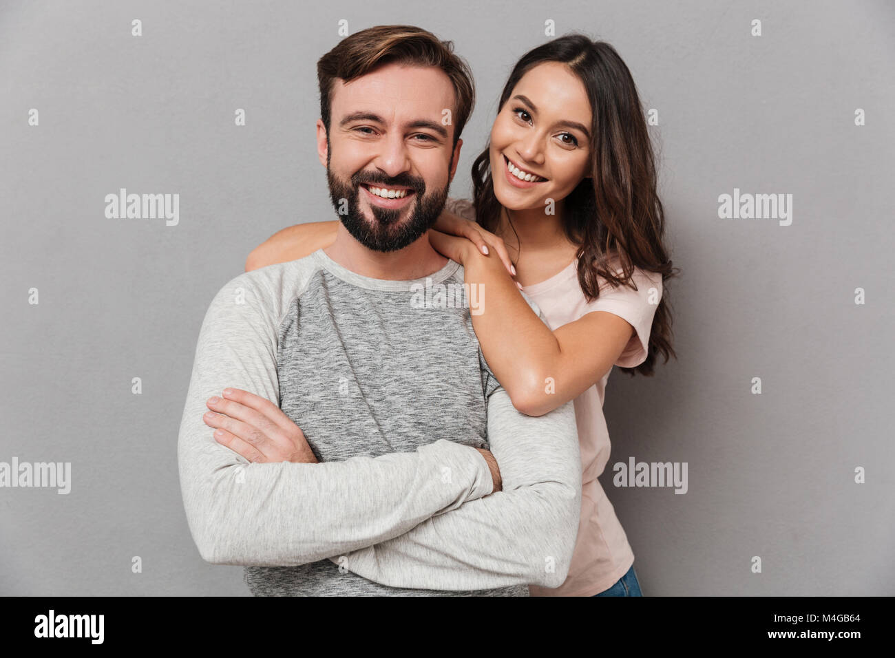 Portrait of a beautiful young couple hugging and looking at camera over ...