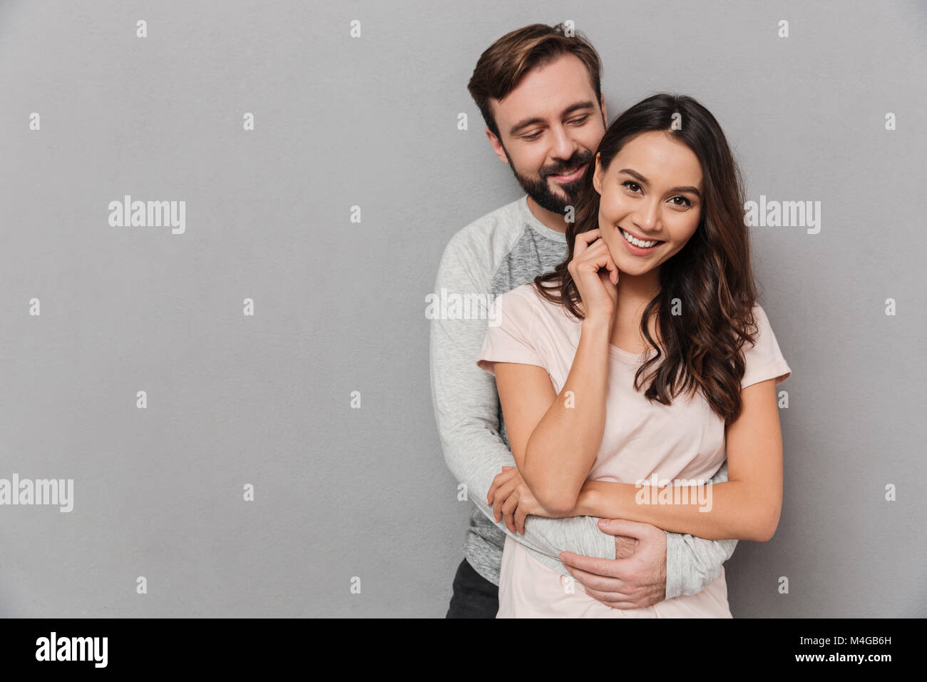 Portrait of a pretty young couple hugging and looking at camera with ...