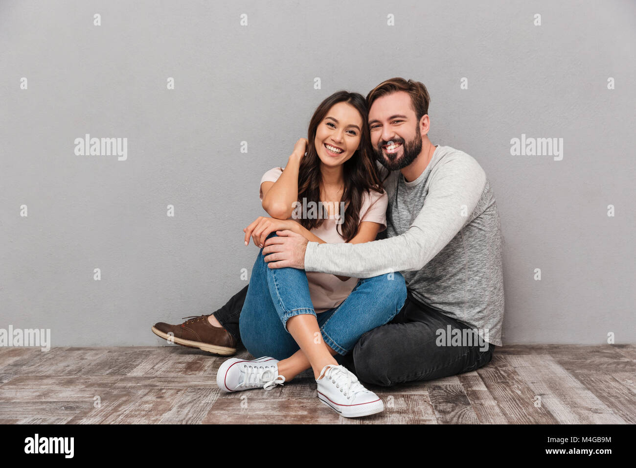 Portrait of a happy young couple hugging while sitting together and ...