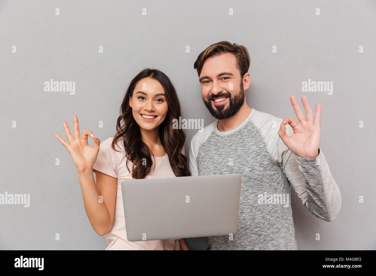 Portrait of a satisfied young couple using laptop computer while ...