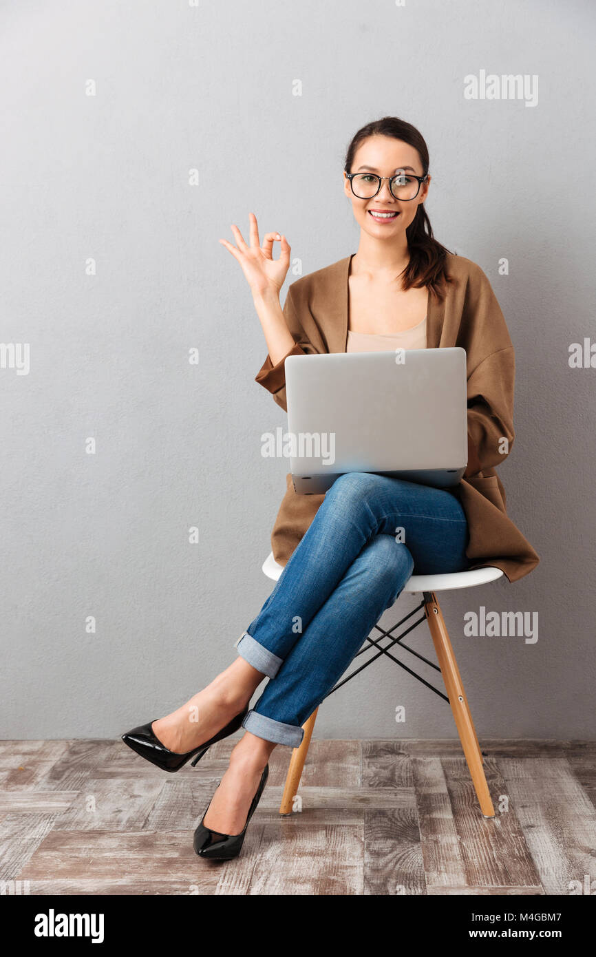 Full length portrait of a confident casual businesswoman holding laptop ...