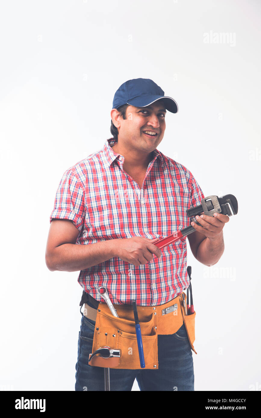 Indian plumber posing with Pipe wrench or plumbing spanner, standing ...