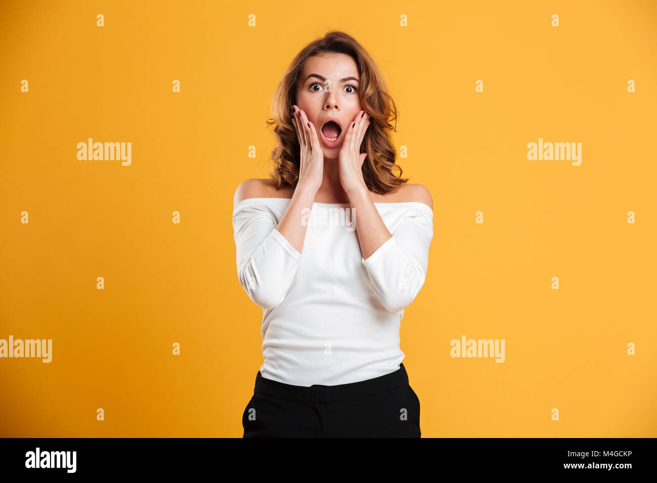 Image of shocked young woman standing isolated over yellow background ...