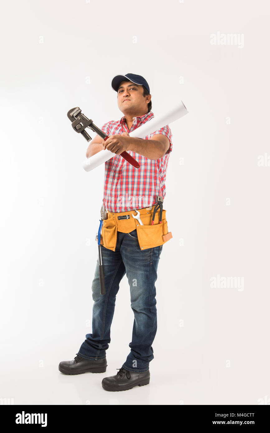 Indian plumber posing with Pipe wrench or plumbing spanner, standing ...