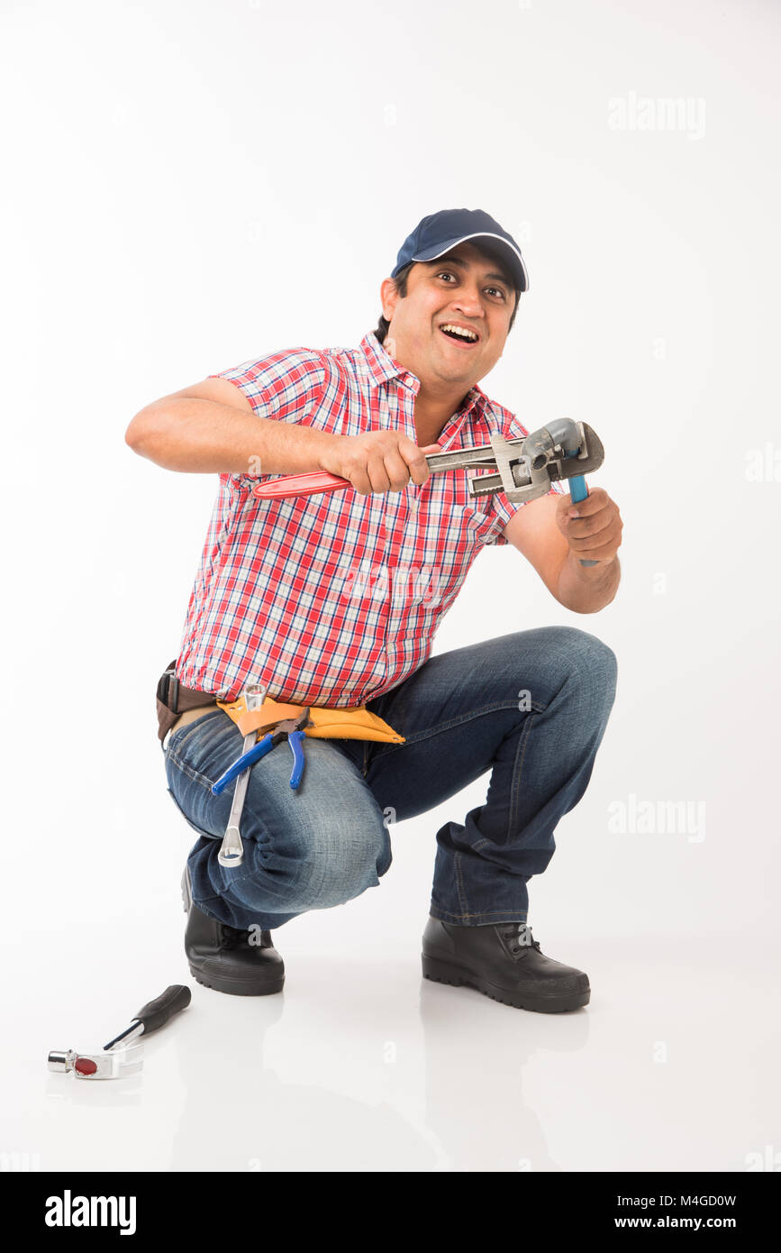 Indian plumber posing with Pipe wrench or plumbing spanner, standing ...