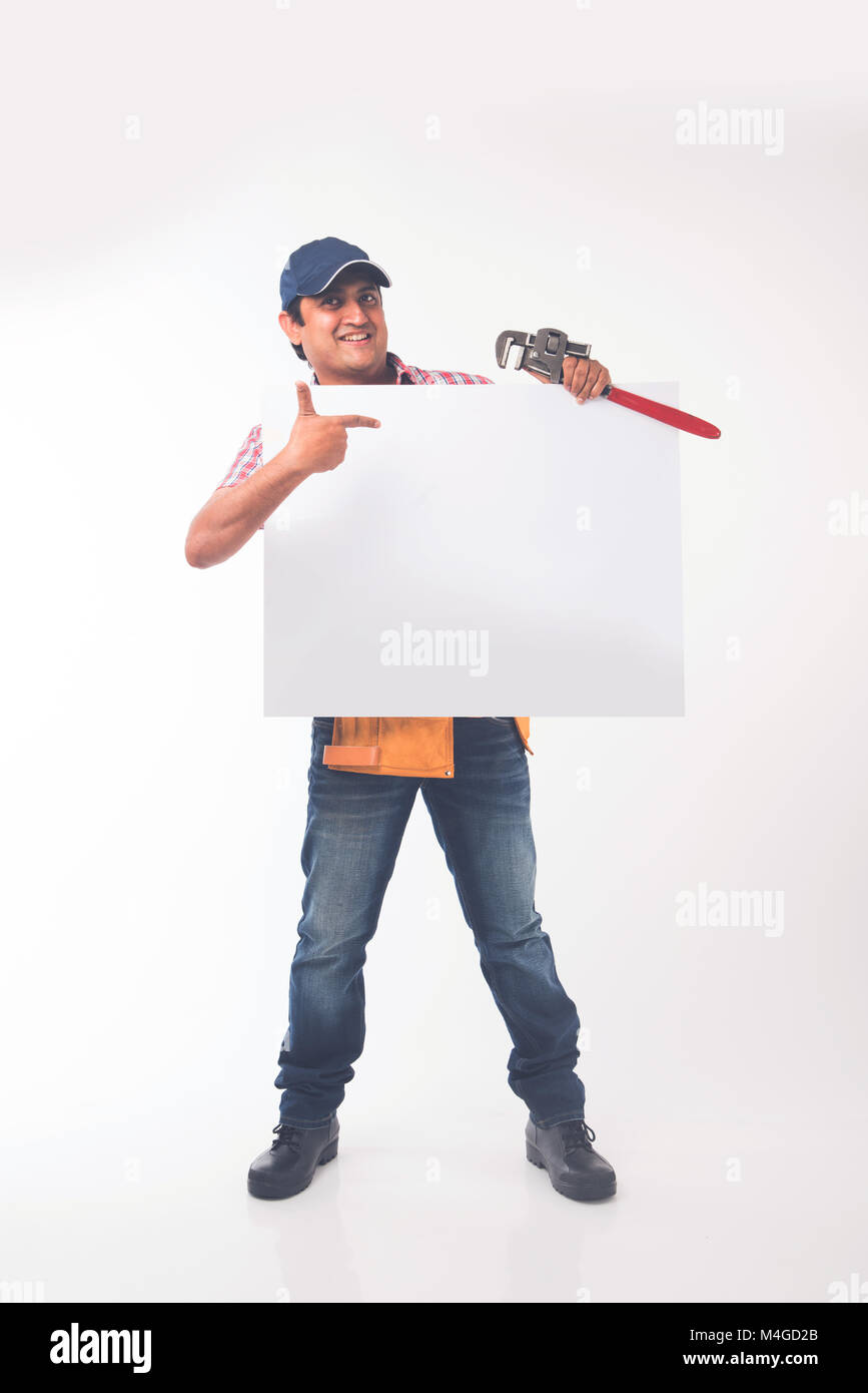 Indian plumber posing with Pipe wrench or plumbing spanner, standing ...