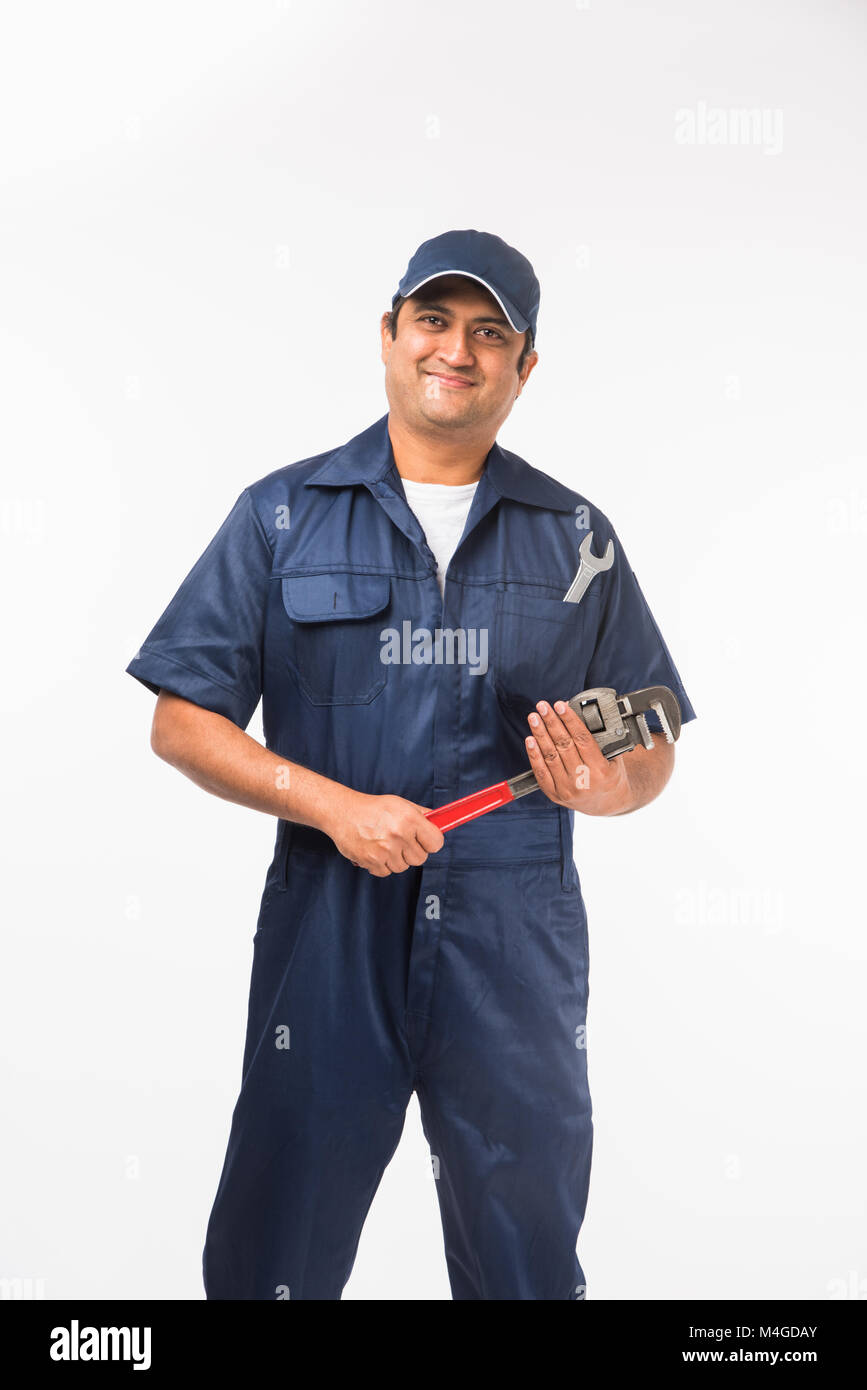 Indian plumber posing with Pipe wrench or plumbing spanner, standing ...