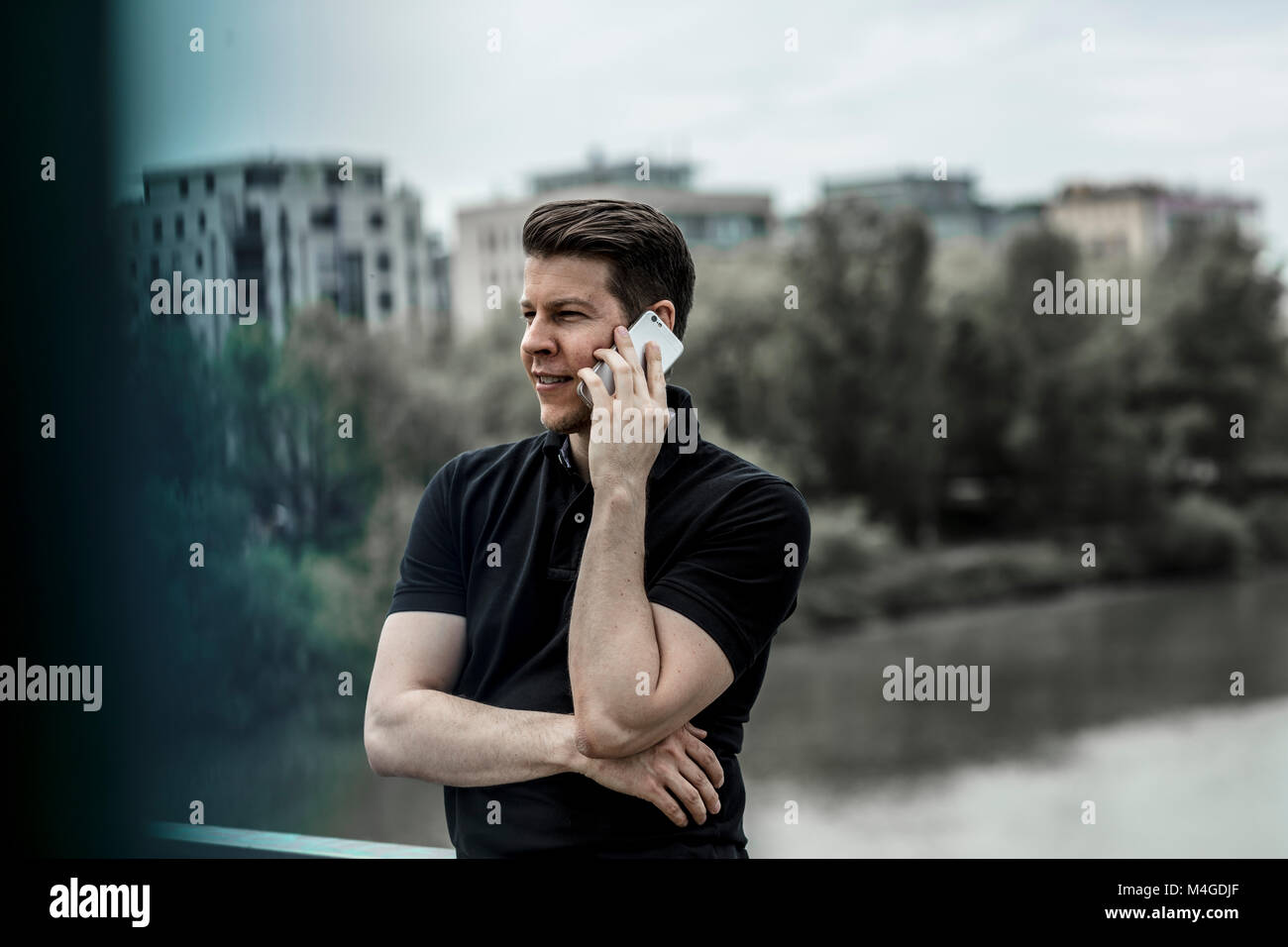 Medium shot of a man talking on a mobile phone. City buildings in and a ...