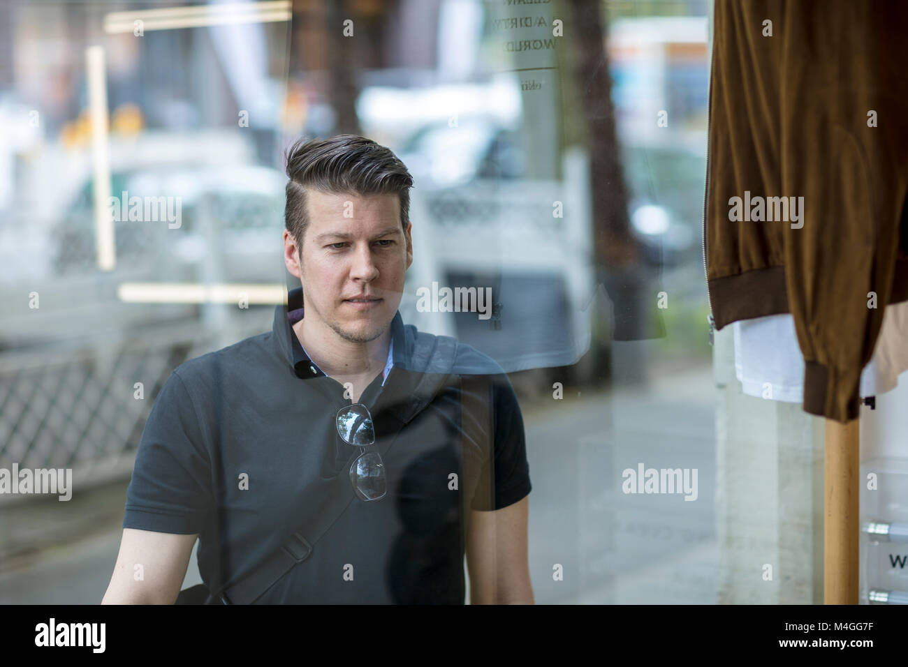 A man looking at clothing through a store window Stock Photo - Alamy