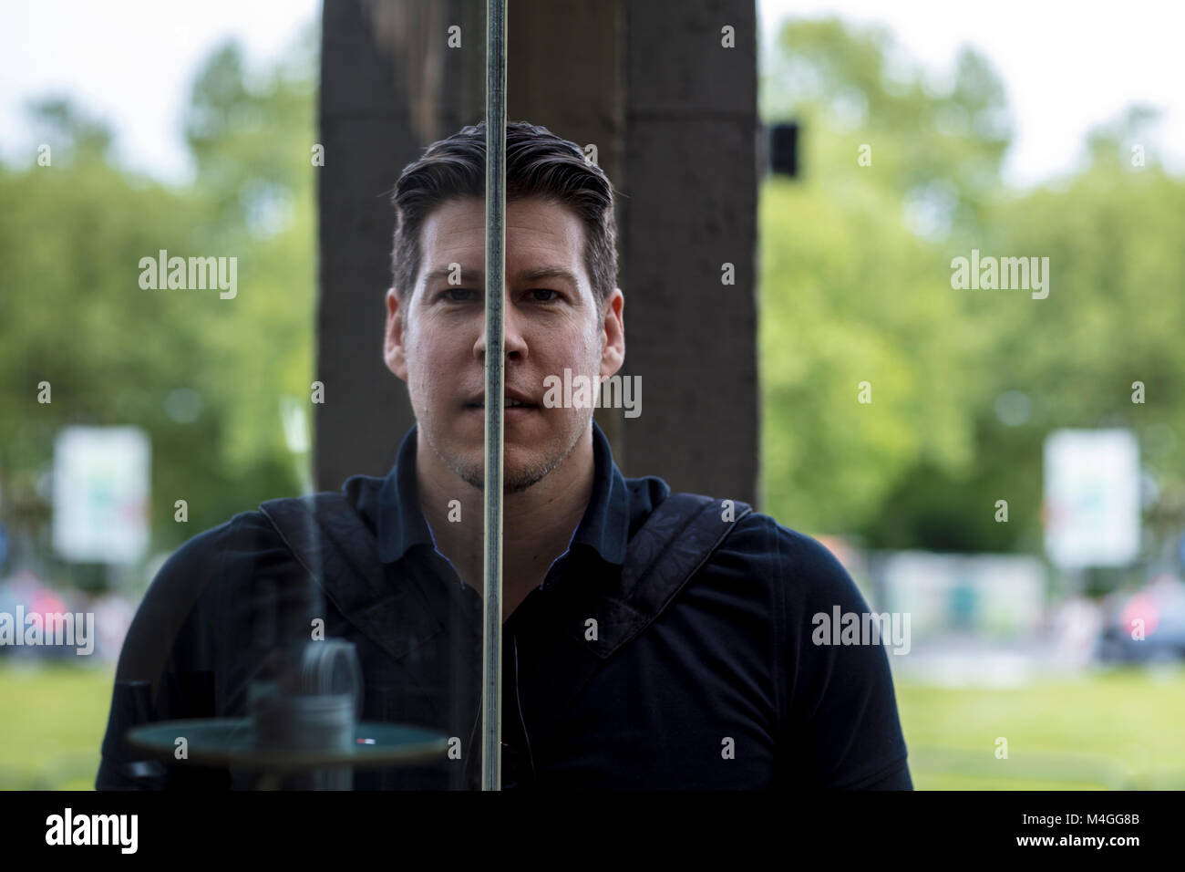Man posing in front of glass window reflecting his image. Close up ...