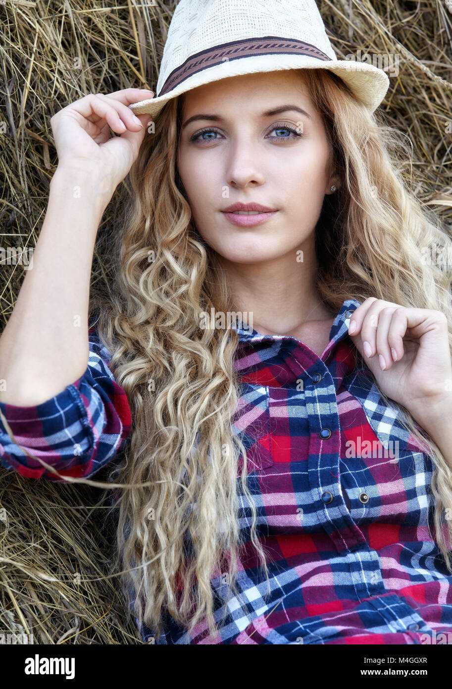 Young blonde country girl in hat sit near haystacks Stock Photo - Alamy